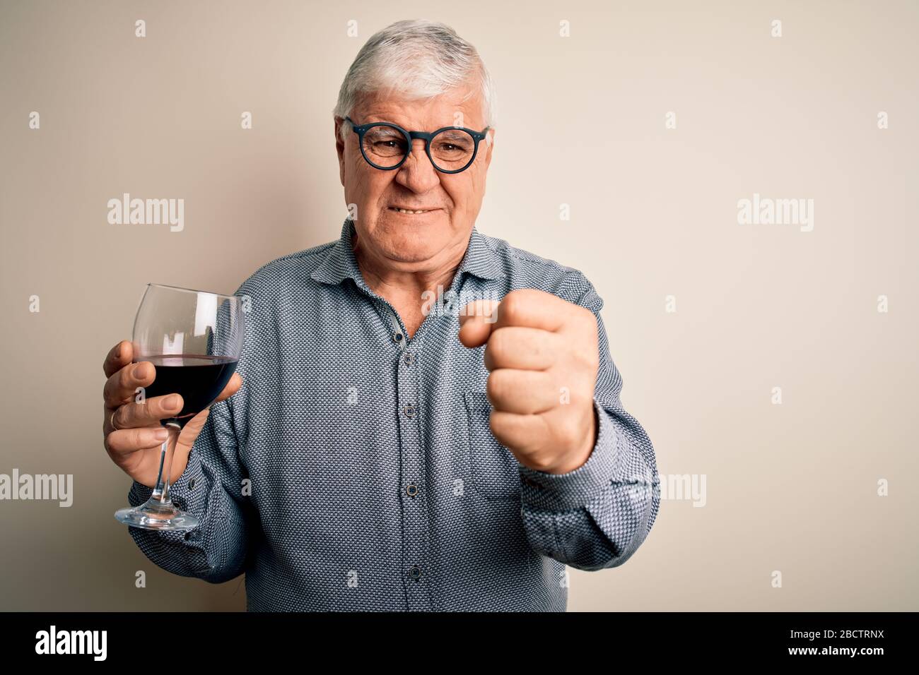 Senior handsome hoary man drinking glass of red wine over isolated ...