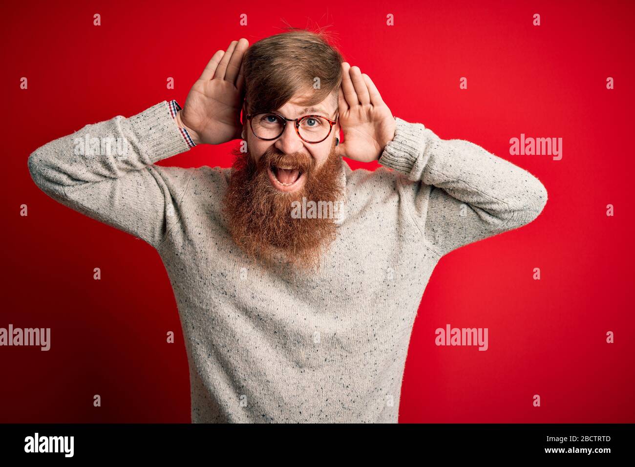 Handsome Irish redhead man with beard wearing casual sweater and ...
