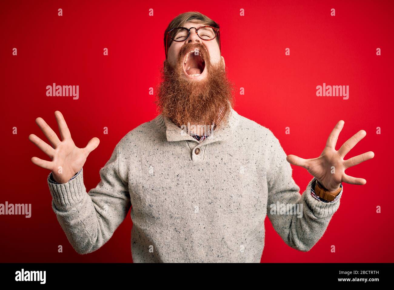 Handsome Irish redhead man with beard wearing casual sweater and ...