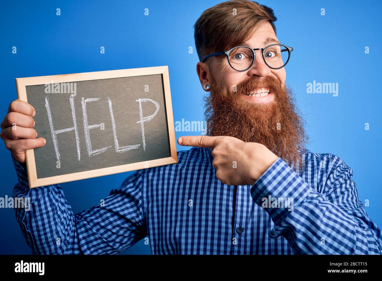 Redhead Irish man with beard holding blackboard with help message over ...