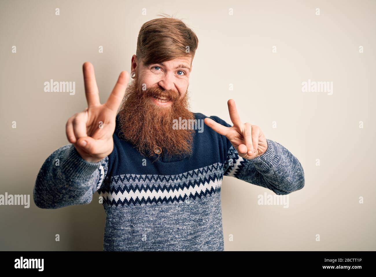 Handsome Irish redhead man with beard wearing winter sweater over ...