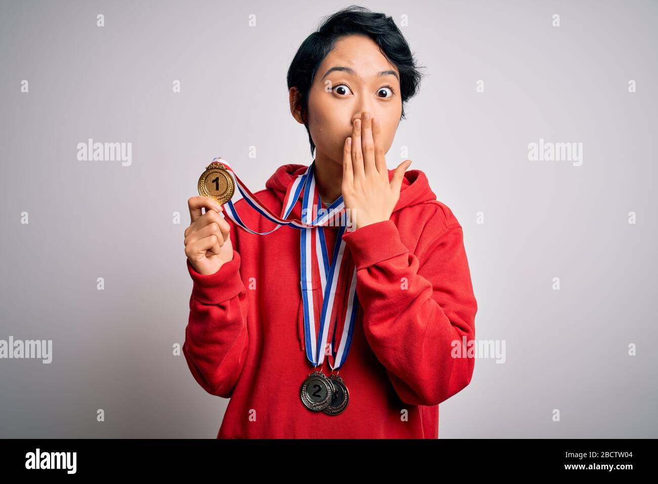 Young beautiful asian girl winner wearing medals over isolated white ...