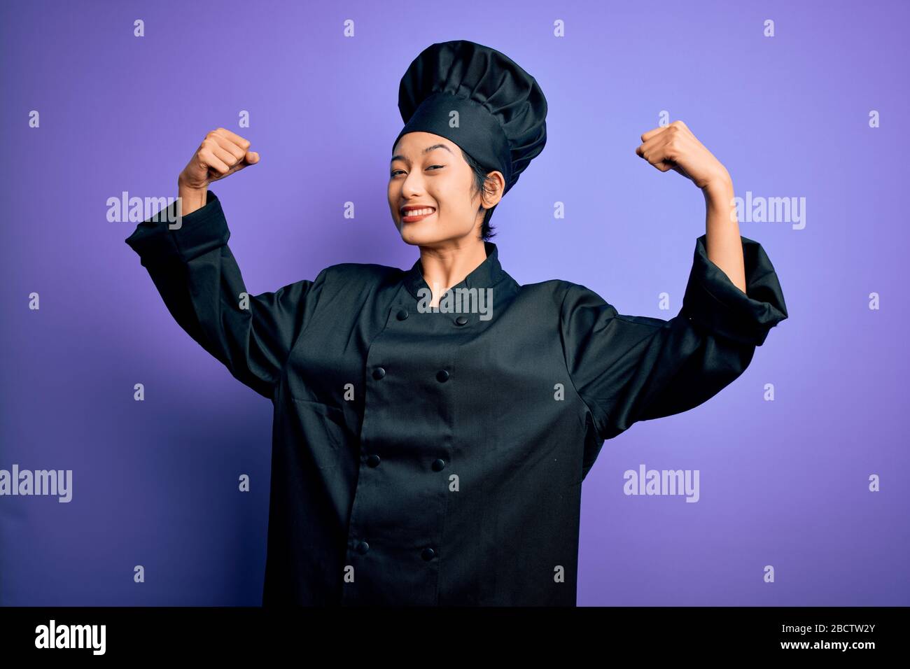 Young beautiful chinese chef woman wearing cooker uniform and hat over ...