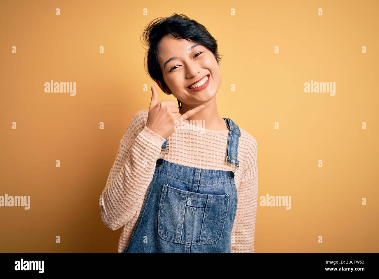 Young beautiful asian girl wearing casual denim overalls over isolated ...