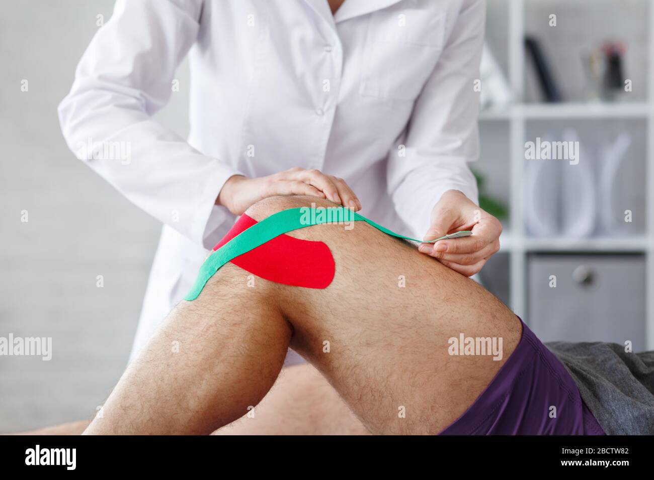 Kinesiology taping.Physical therapist applying kinesiology tape to patient knee.Therapist ...