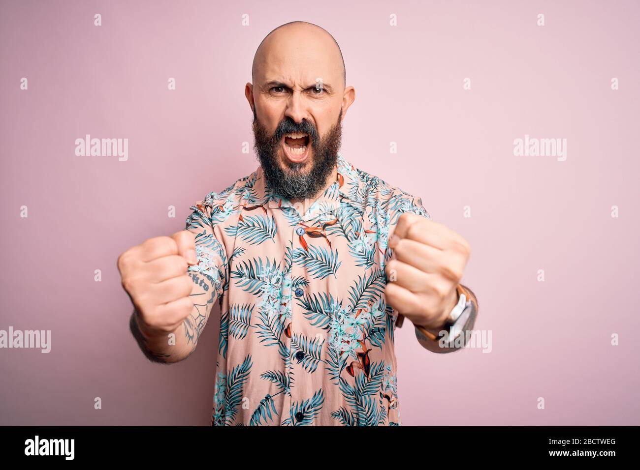 Handsome bald man with beard and tattoo wearing casual floral shirt ...