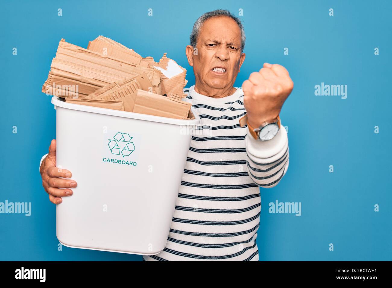 Senior man recycling holding trash can with cardboard to recycle over ...