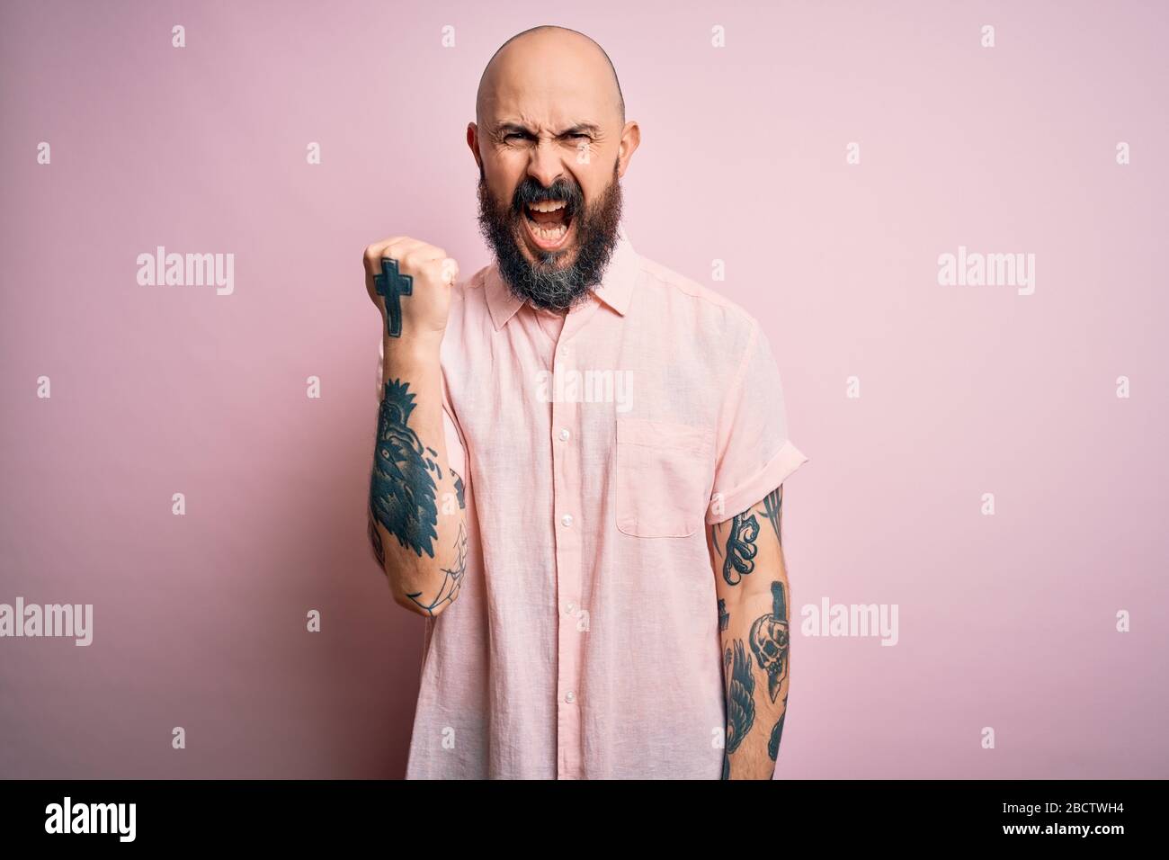 Handsome bald man with beard and tattoo wearing casual shirt over ...