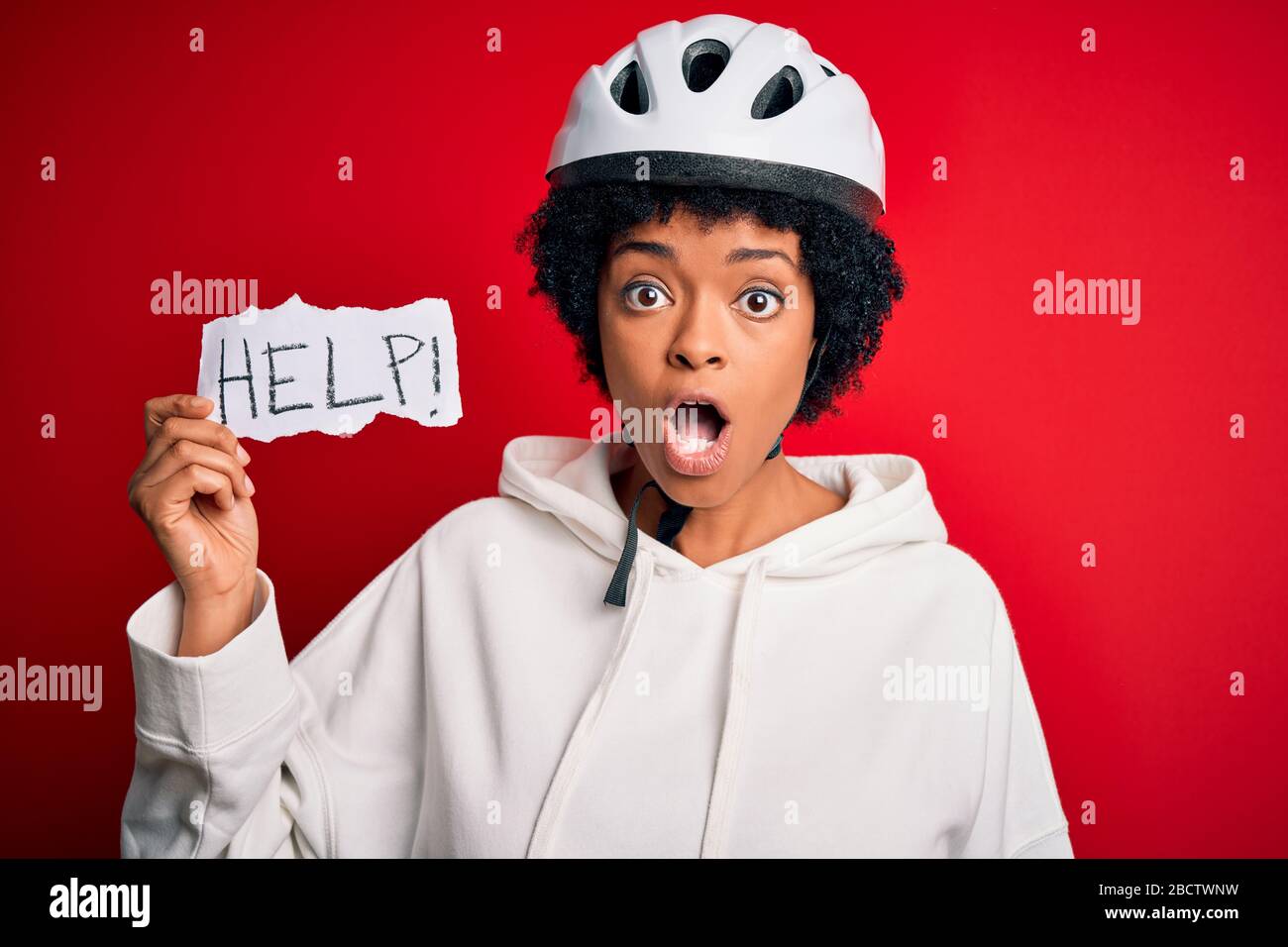 African American woman with curly hair wearing bike helmet holding ...