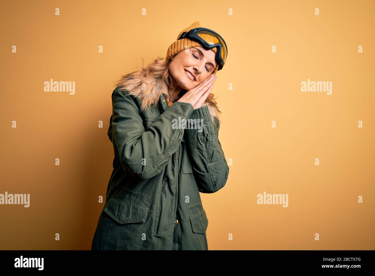 Middle age beautiful blonde skier woman wearing snow sportwear and ski ...