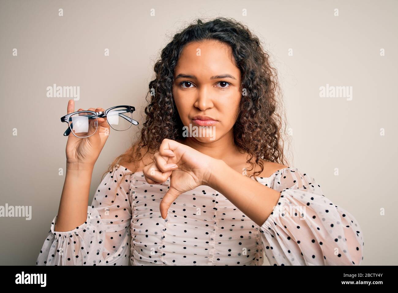 Young beautiful optical woman with curly hair holding vision glasses ...