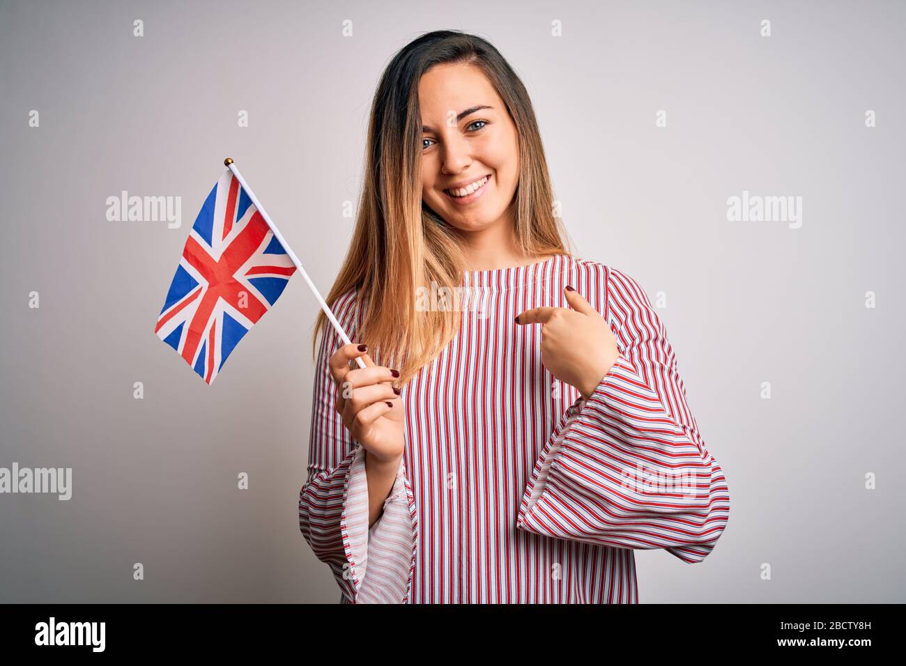 Young beautiful blonde woman with blue eyes holding united kingdom flag ...