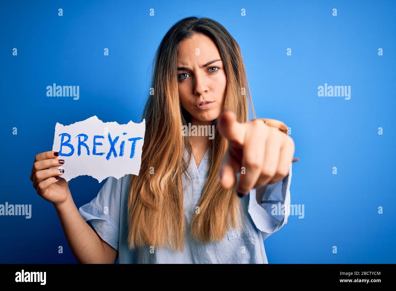 Young beautiful blonde woman with blue eyes holding banner with brexit ...