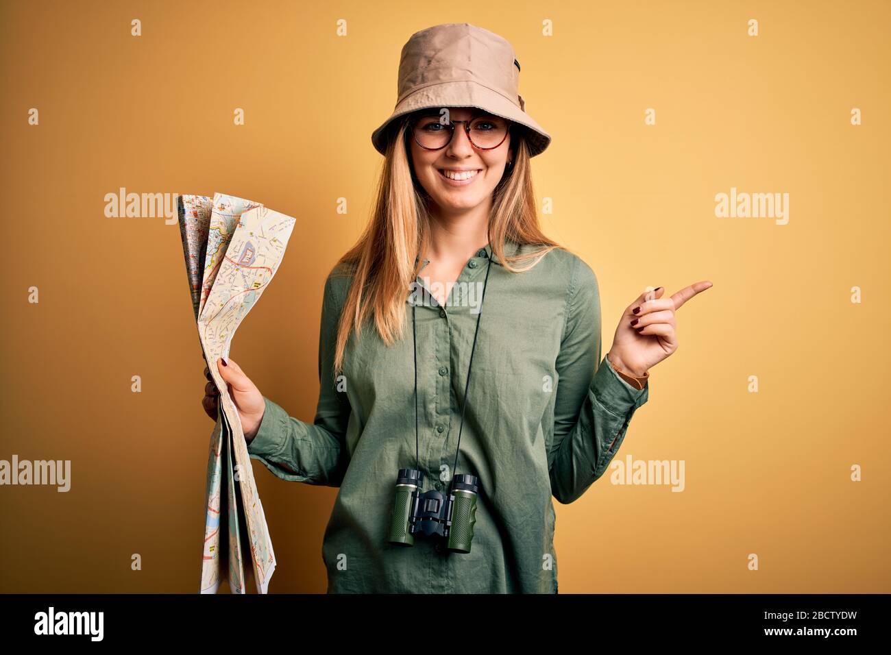 Blonde explorer woman with blue eyes on vacation wearing hat and ...