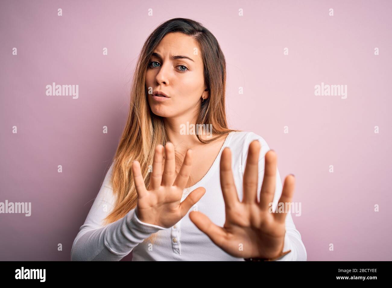 Young beautiful blonde woman with blue eyes wearing white t-shirt over ...