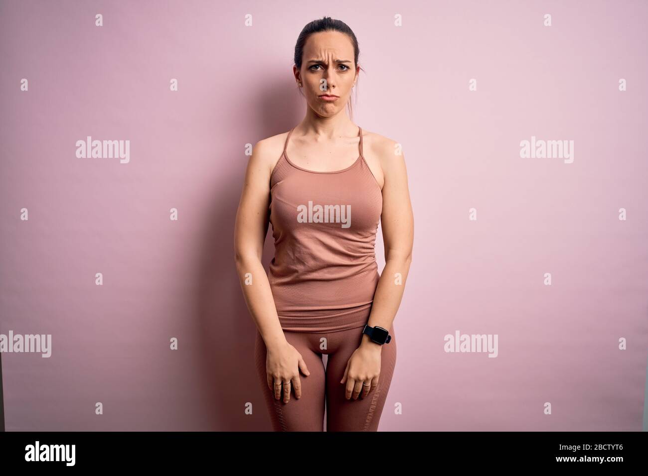 Young blonde fitness woman wearing sport workout clothes over pink ...