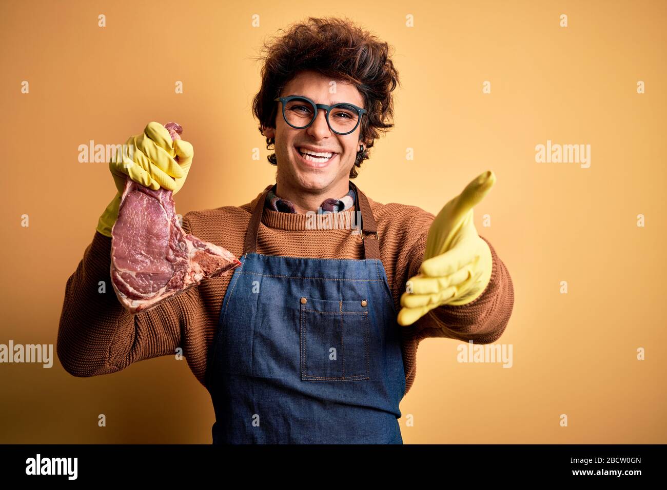 Young handsome butcher man holding meet steak standing over isolated ...