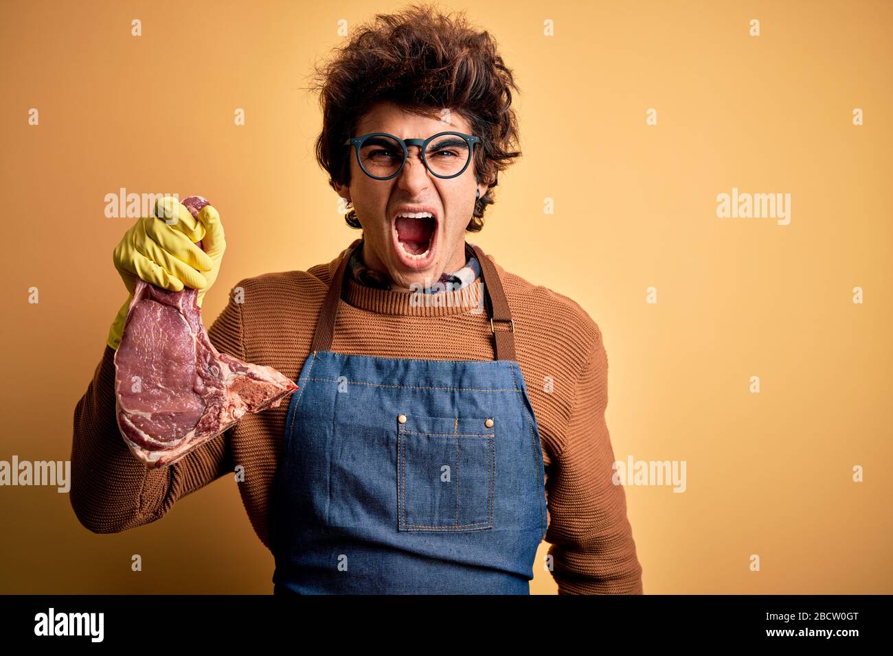 Young handsome butcher man holding meet steak standing over isolated ...