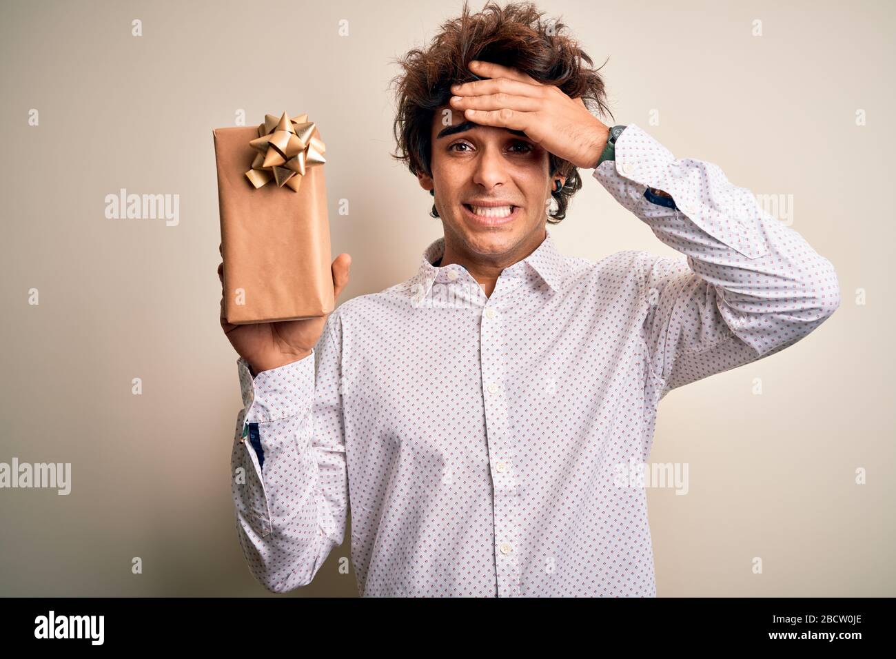 Young handsome man holding birthday gift standing over isolated white ...
