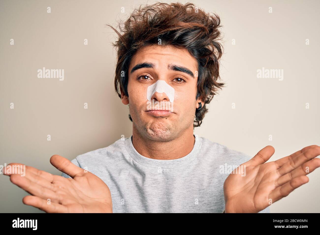 Young handsome man using nose strip standing over isolated white ...