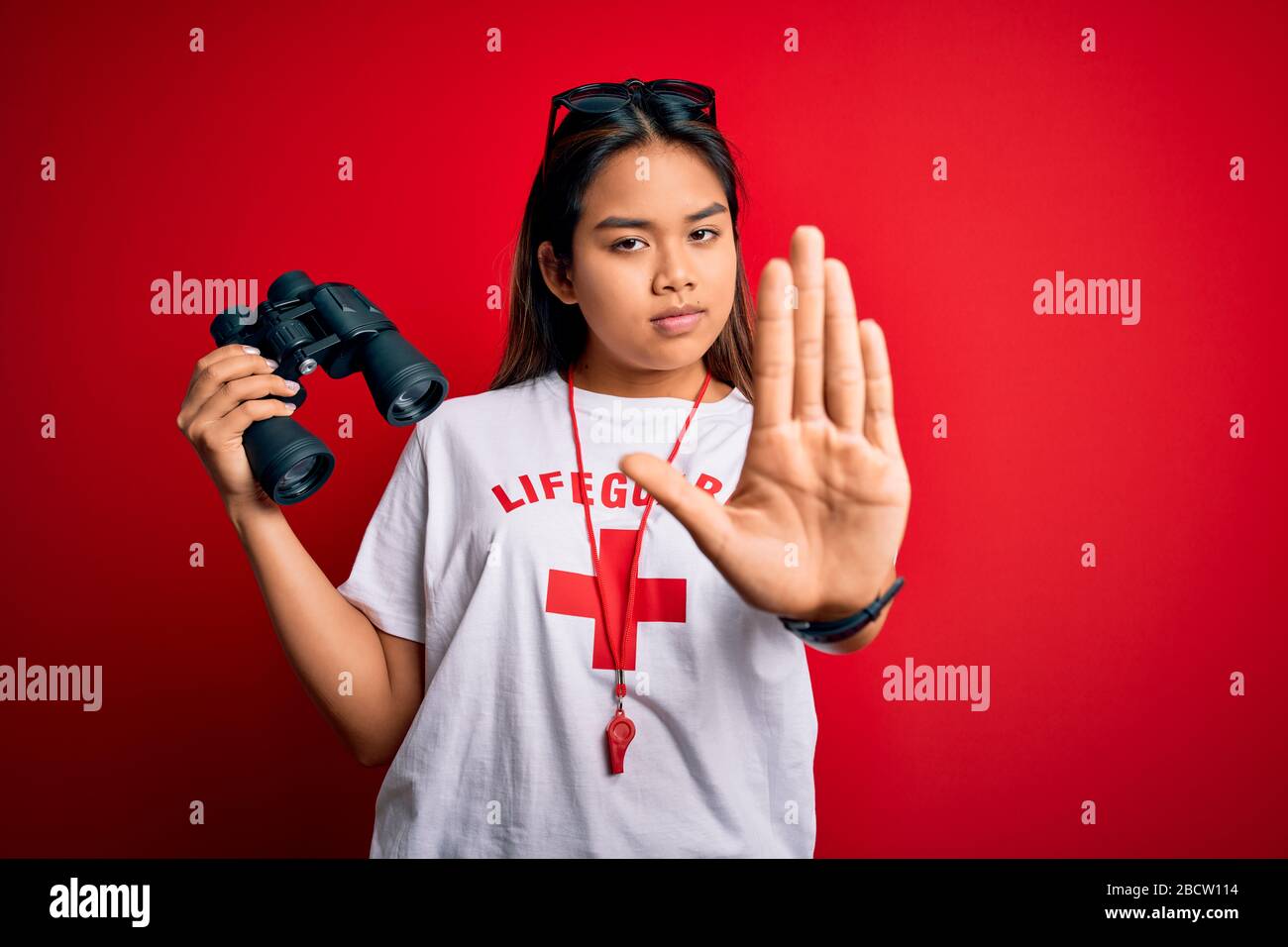 Young asian lifeguard girl wearing t-shirt with red cross using whistle ...