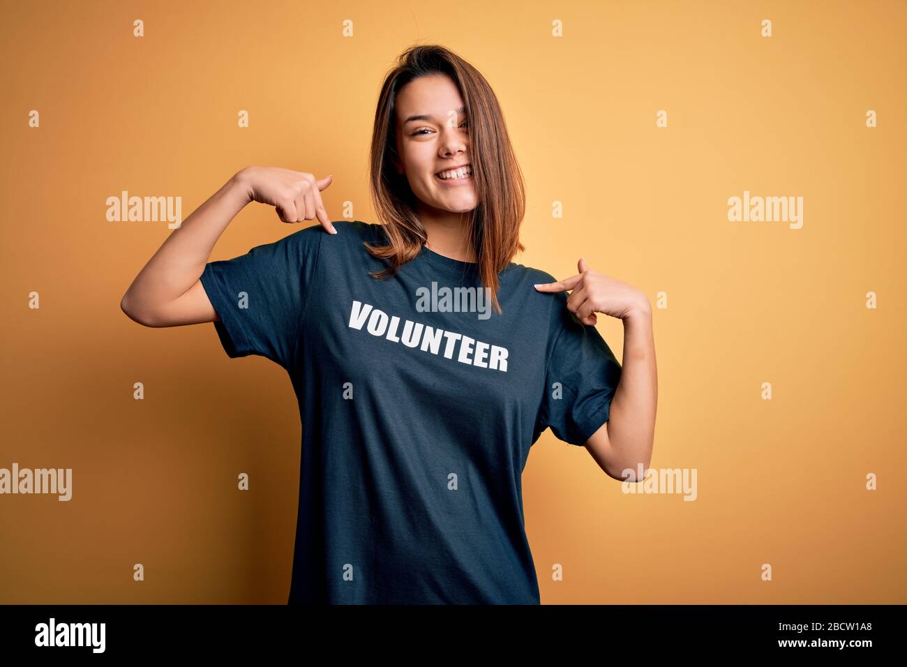 Young beautiful brunette girl doing volunteering wearing t-shirt with ...