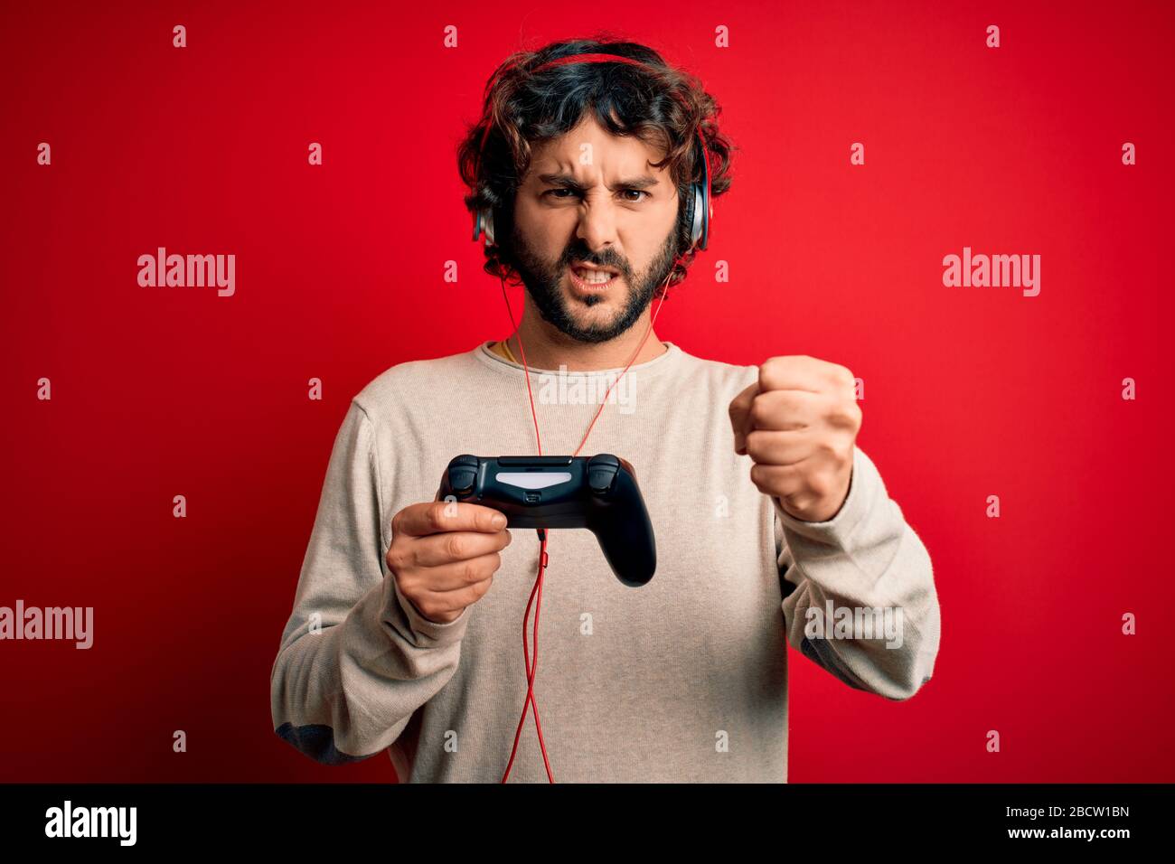 Young gamer man with curly hair and beard playing video game using ...
