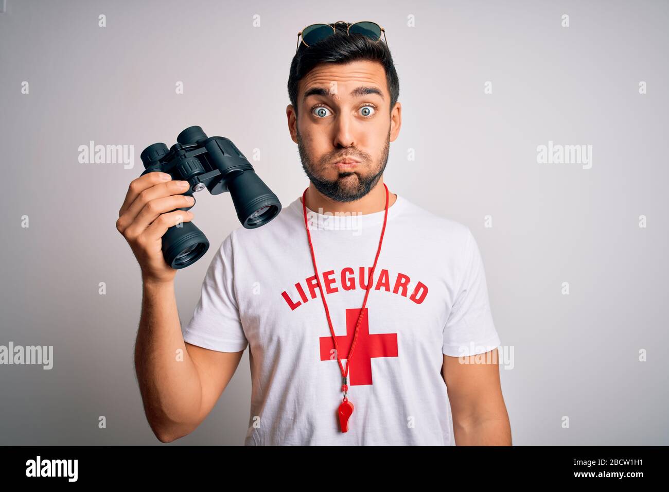 Young lifeguard man with beard wearing t-shirt with red cross and ...