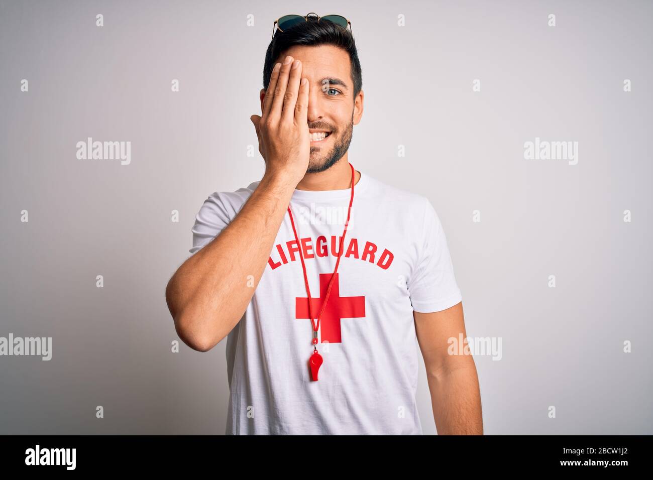 Young handsome lifeguard man with beard wearing t-shirt with red cross ...
