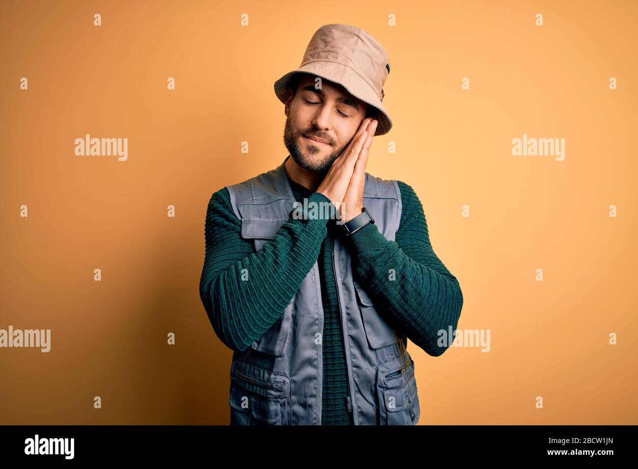 Handsome tourist man with beard on vacation wearing explorer hat over ...