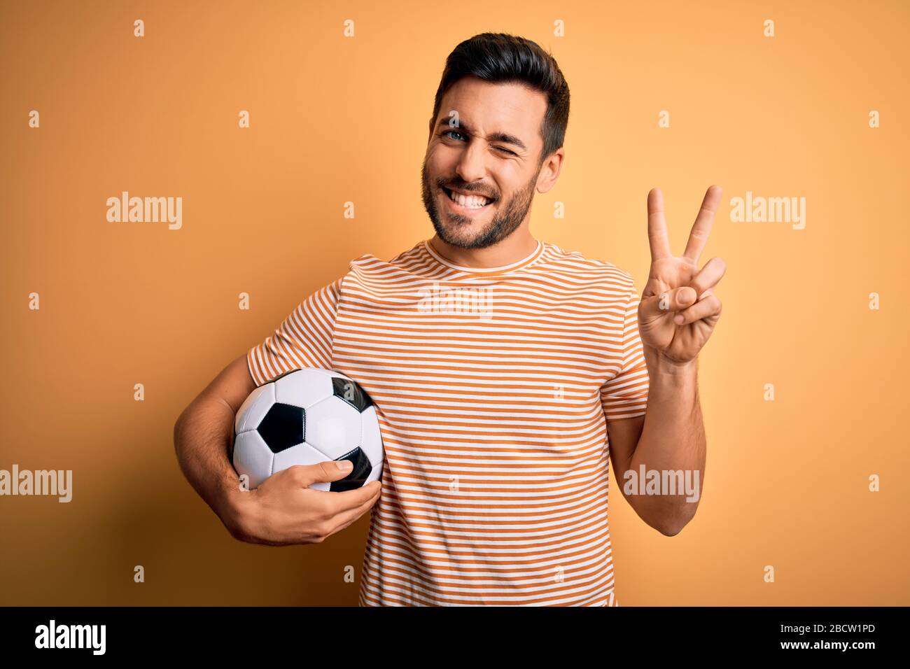 Handsome player man with beard playing soccer holding footballl ball ...