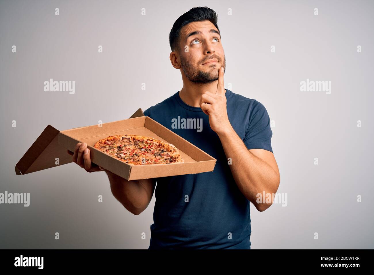 Young handsome man holding delivery box with delicious Italian pizza ...