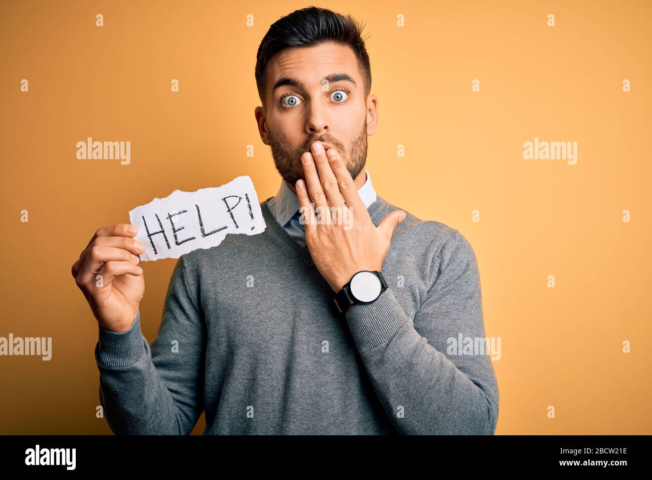 Young overworked business man asking for help holding paper over yellow ...