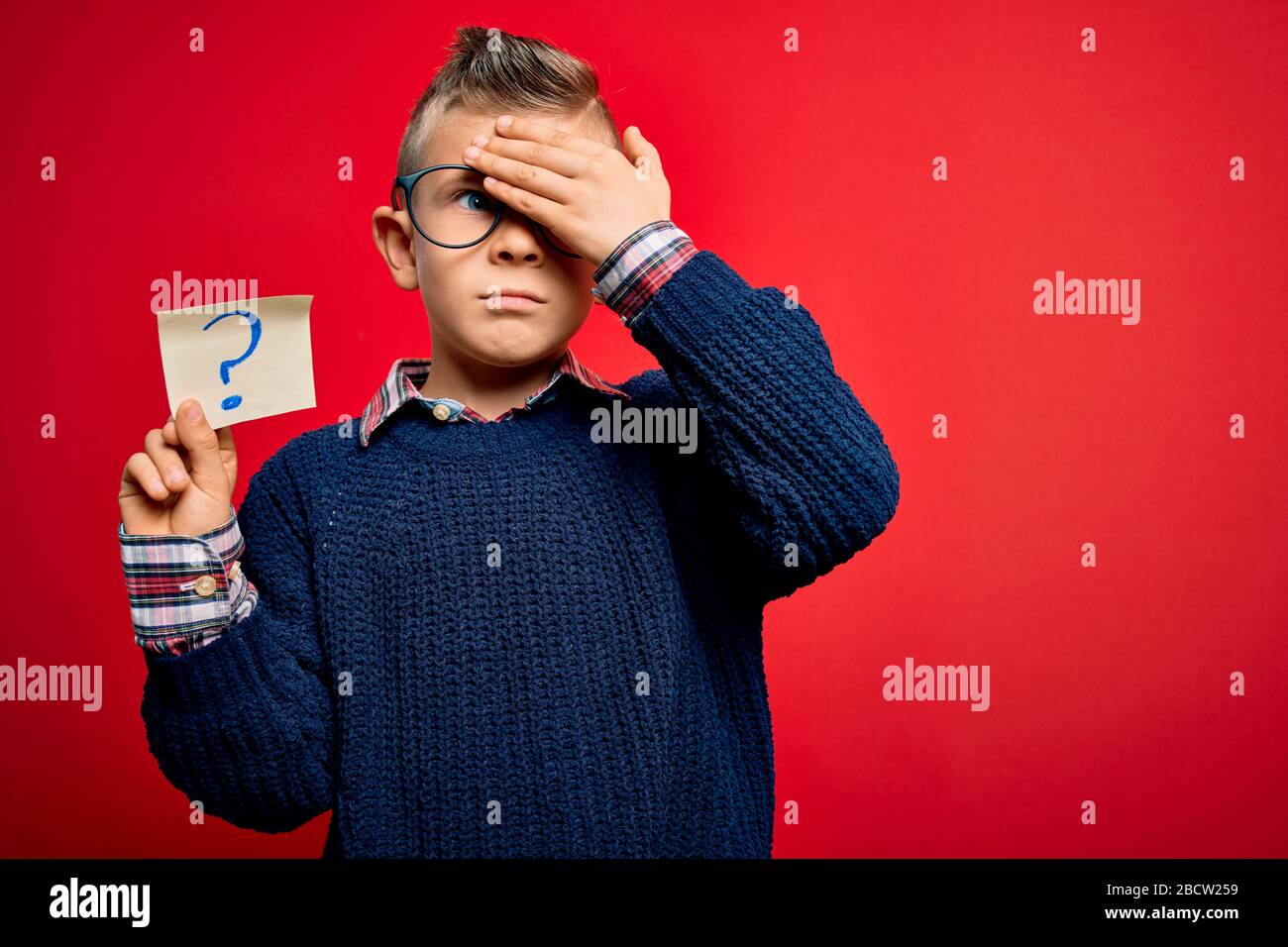 Young little caucasian kid wearing glasses holding paper note with ...