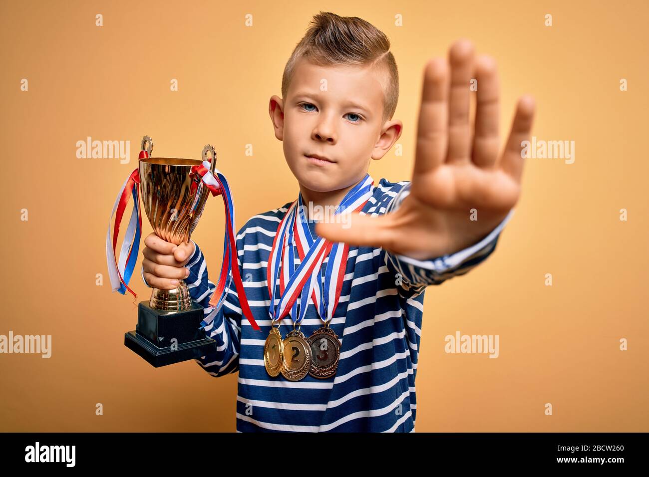 Young little caucasian kid wearing winner medals and victory award ...