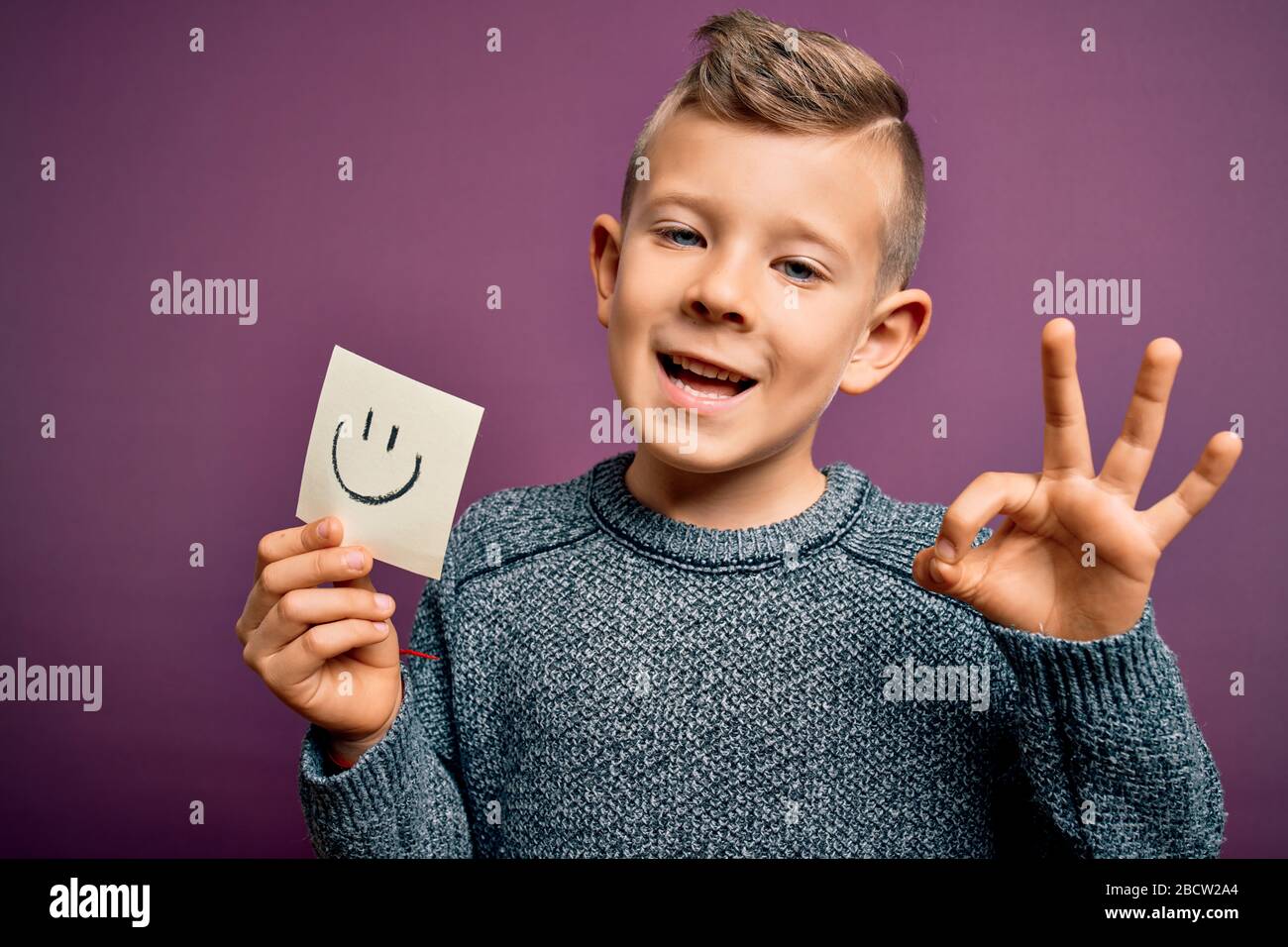 Young little caucasian kid showing smiley face on a paper note as happy ...