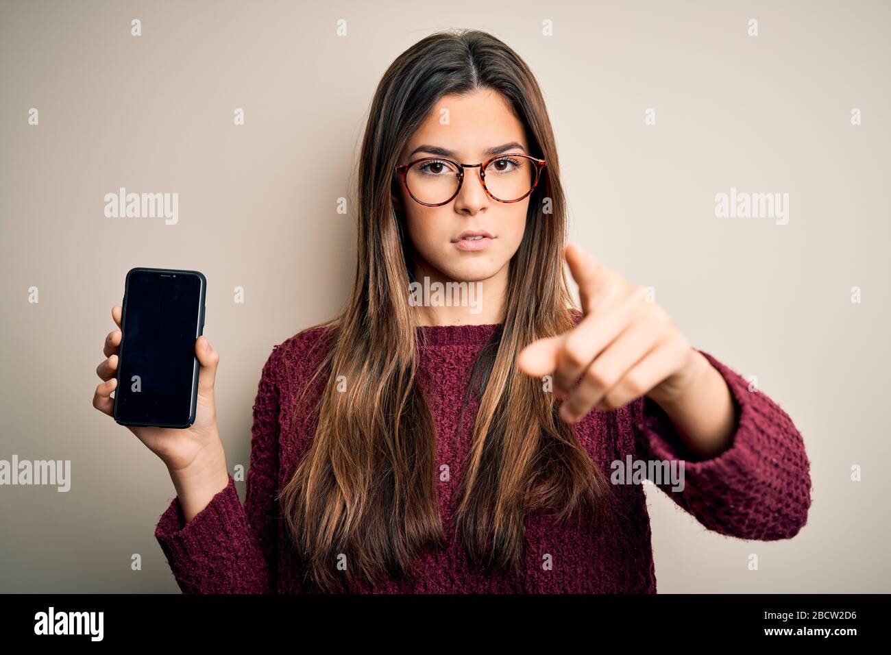 Young beautiful girl wearing glasses showing smartphone over isolated ...