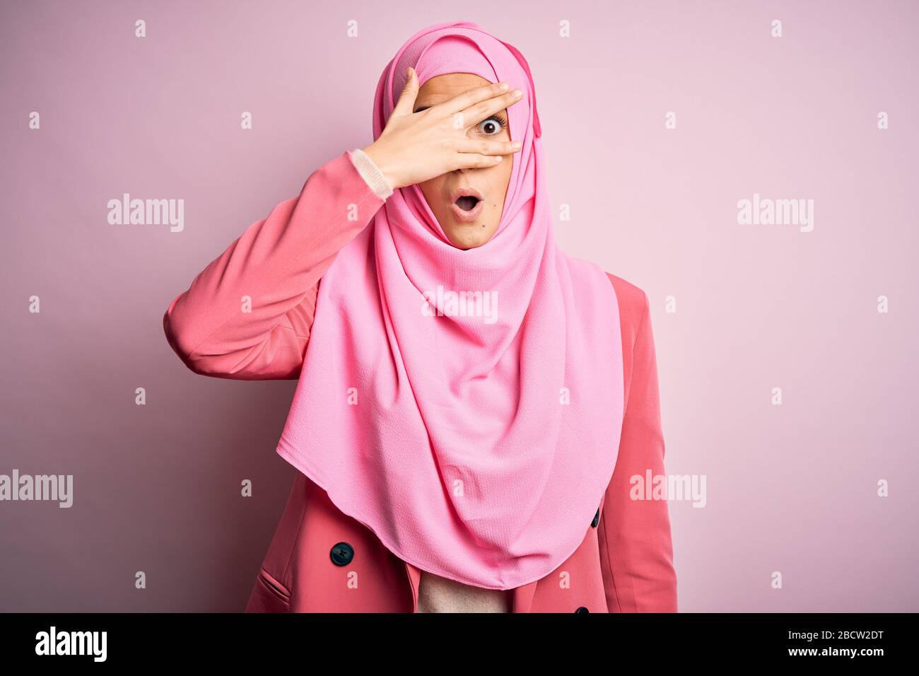 Young beautiful girl wearing muslim hijab standing over isolated pink ...