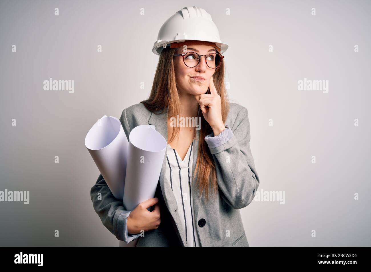 Young beautiful redhead architect woman wearing glasses and safety ... Young beautiful redhead architect woman wearing glasses and safety ...
