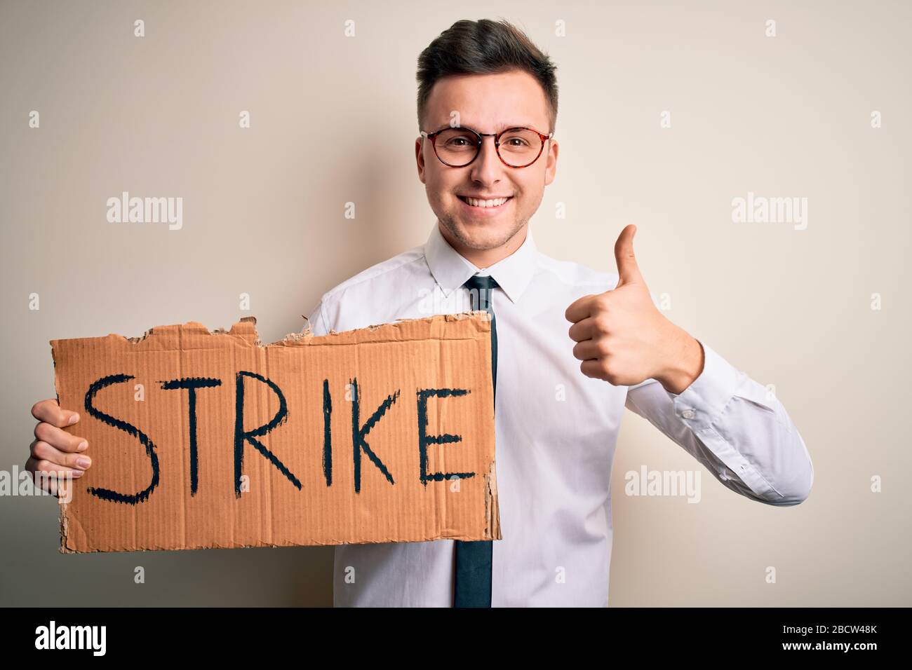 Young handsome caucasian business man holding protest banner on job ...