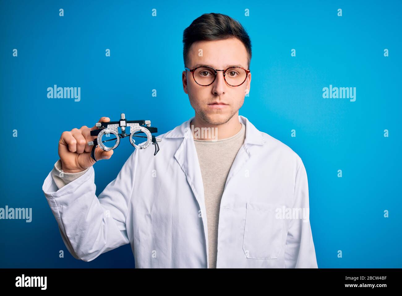 Young handsome professional optic man holding optometrical glasses over ...