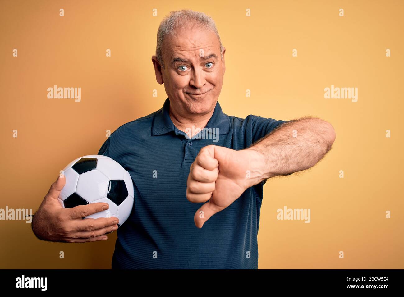 Middle age hoary player man playing soccer holding football ball over ...
