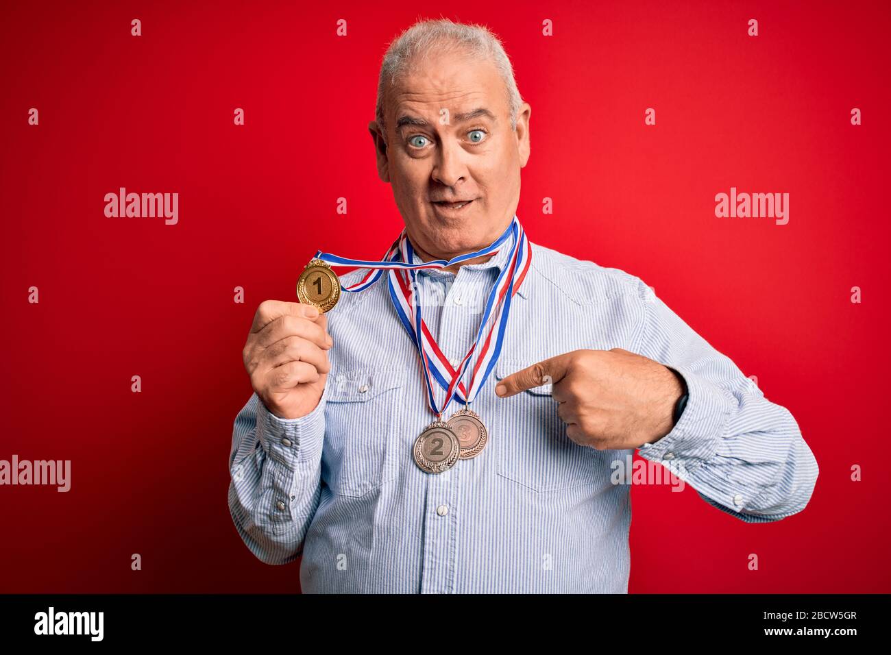 Middle age hoary champion man wearing medals standing over isolated red ...