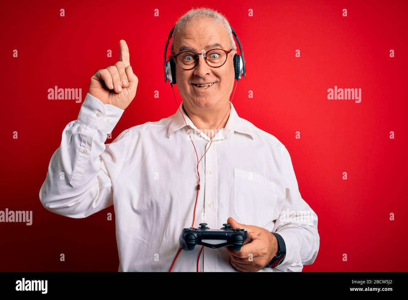 Middle age handsome hoary gamer man playing video game using joystick ...