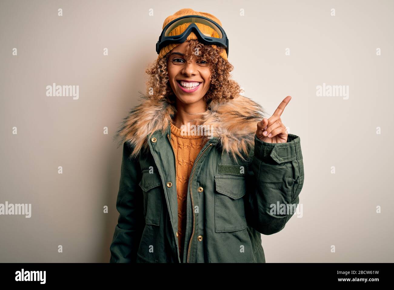 Young african american skier woman with curly hair wearing snow ...