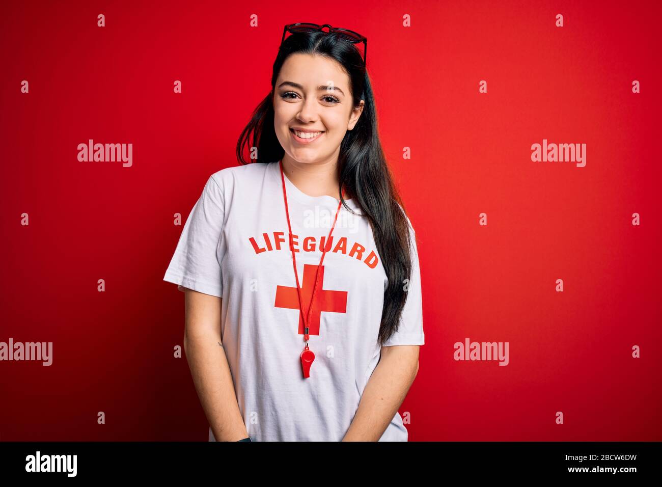 Young lifeguard woman wearing secury guard equipent over red background ...