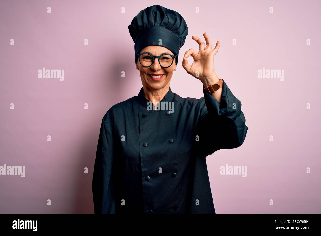 Middle age brunette chef woman wearing cooker uniform and hat over ...