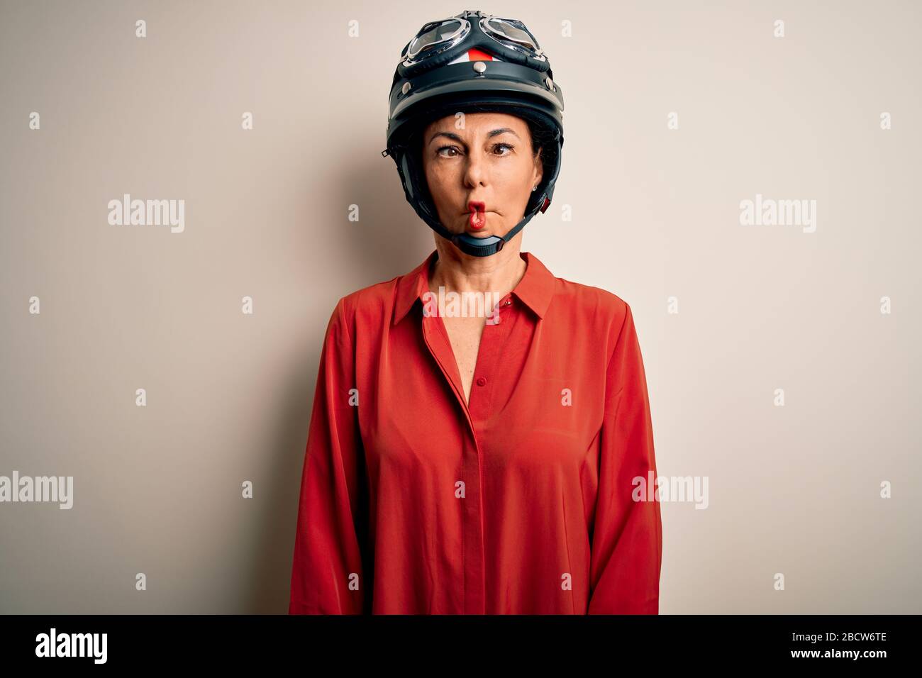 Middle age motorcyclist woman wearing motorcycle helmet over isolated ...