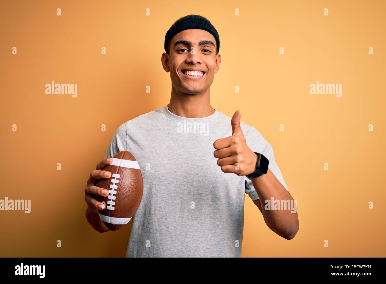 Young handsome african american man holding rugby ball over isolated ...
