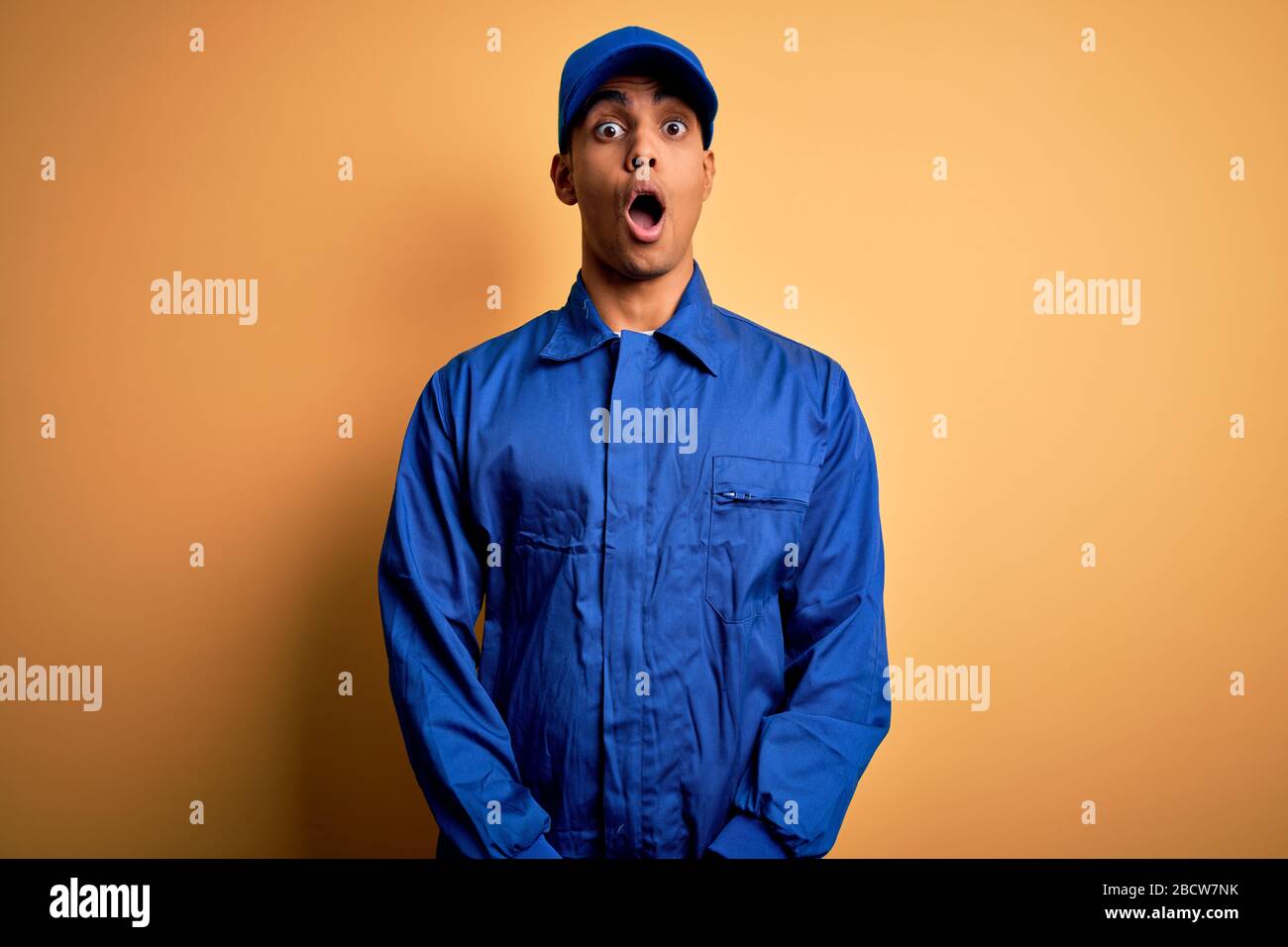 Young african american mechanic man wearing blue uniform and cap over ...